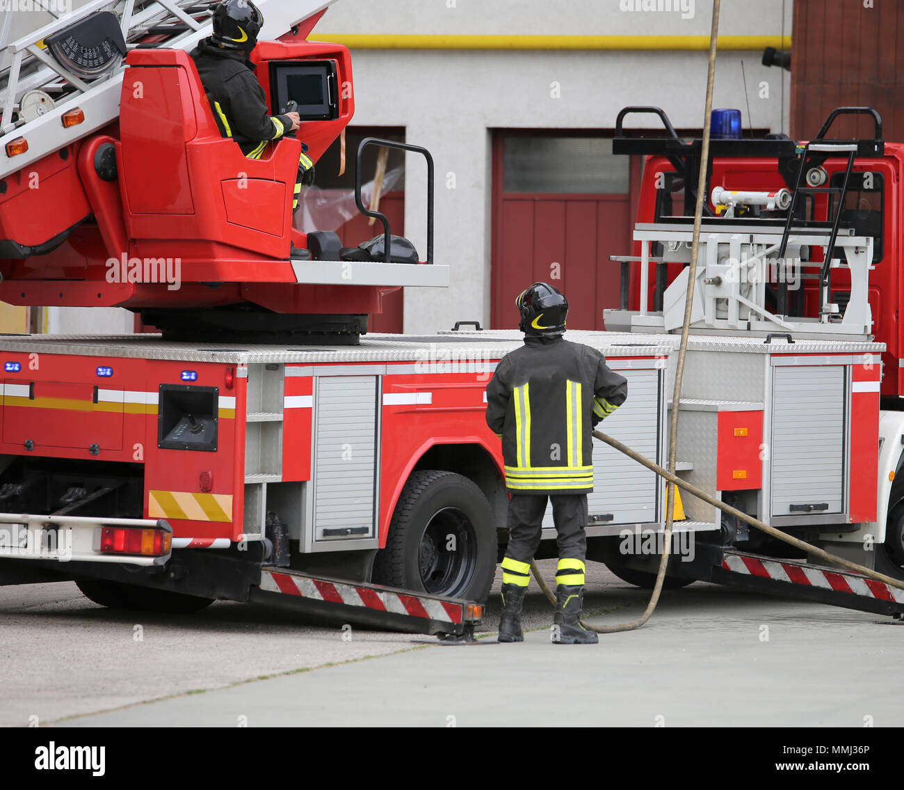 big red fire engine with aerial ladder and firefighters during an ...