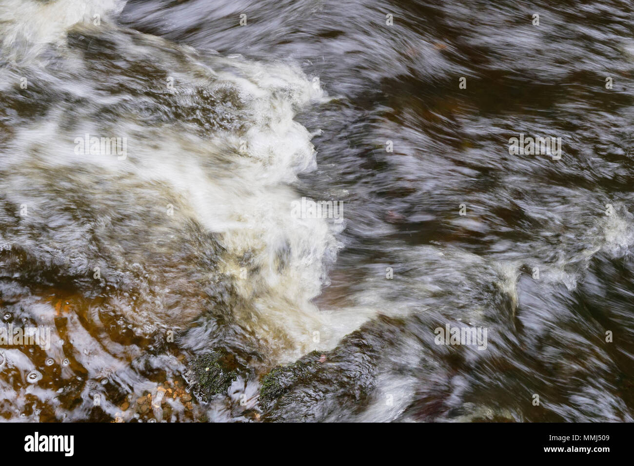 Close up of the surface of a shallow fast flowing stream swirling over ...