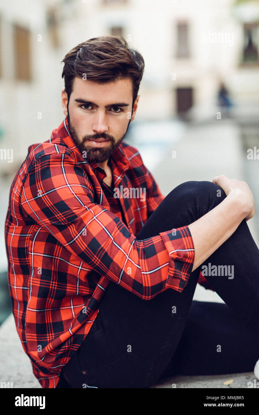 Young bearded man, model of fashion, wearing a plaid shirt with sitting ...