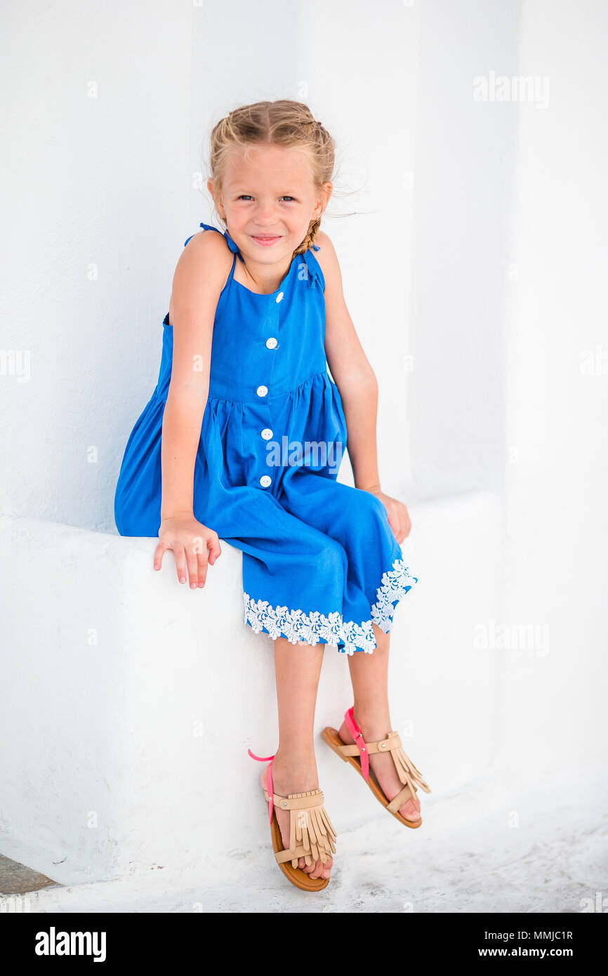 Cute girl in blue dress at street of typical greek traditional village ...