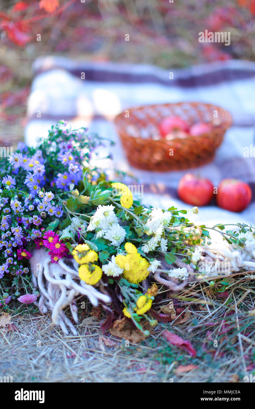 Bouguet of flowers lying on grass, basket with fruits on blanket in ...