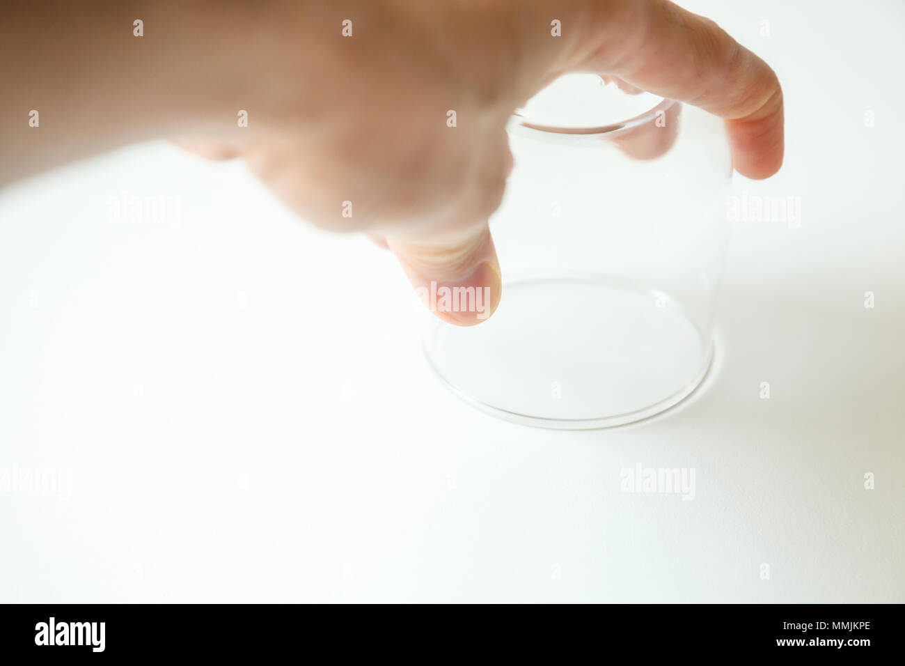 hand hold glass upside down on white background Stock Photo - Alamy