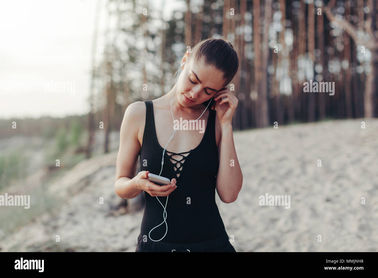 fitness girl with a smartphone on nature background, enjoys sports ...