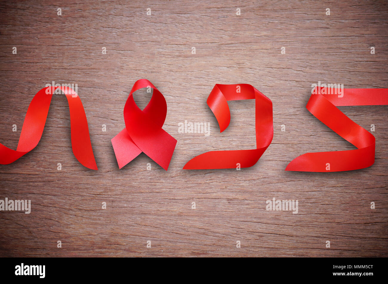 AIDS word in red ribbon on wood background Stock Photo - Alamy