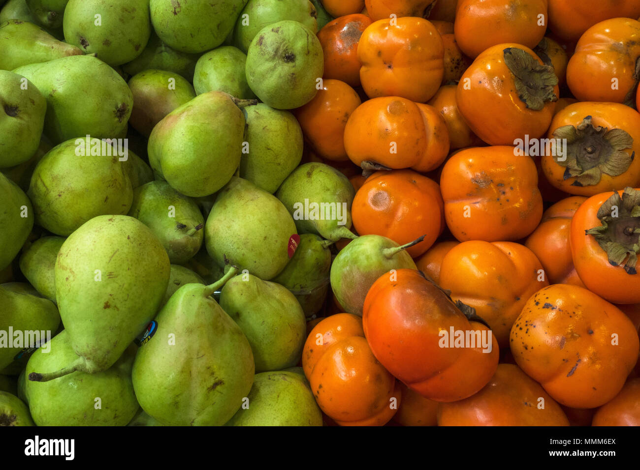 Green pears and orange persimmon, food background of fresh fruits Stock ...