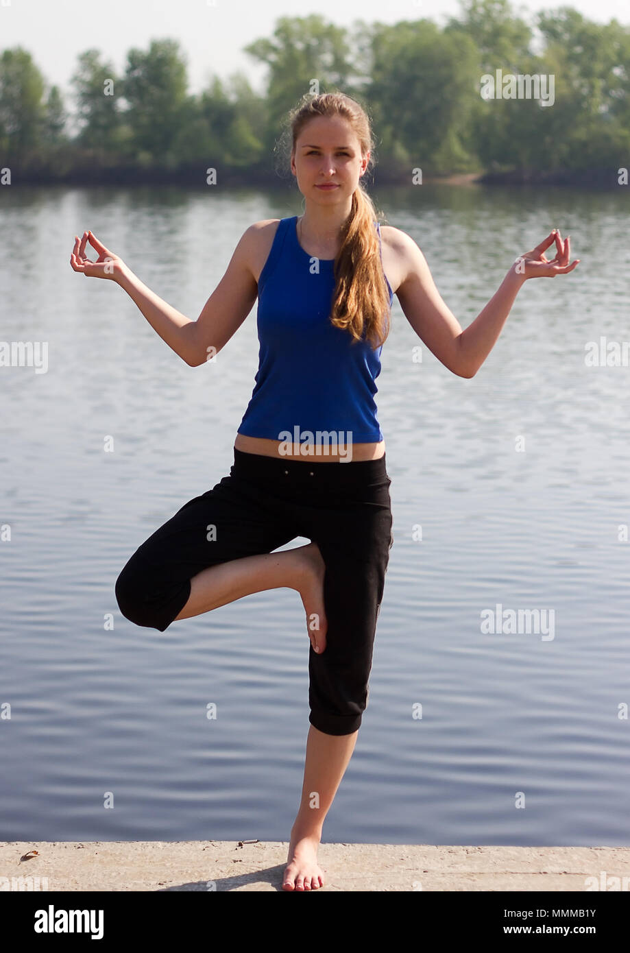 Yoga Woman on a dock by the river Stock Photo - Alamy