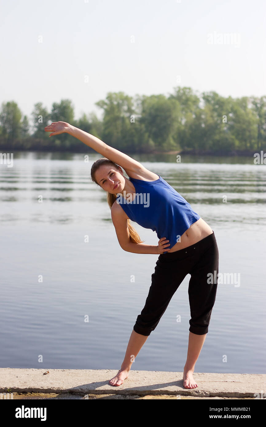 Yoga Woman on a dock by the river Stock Photo - Alamy