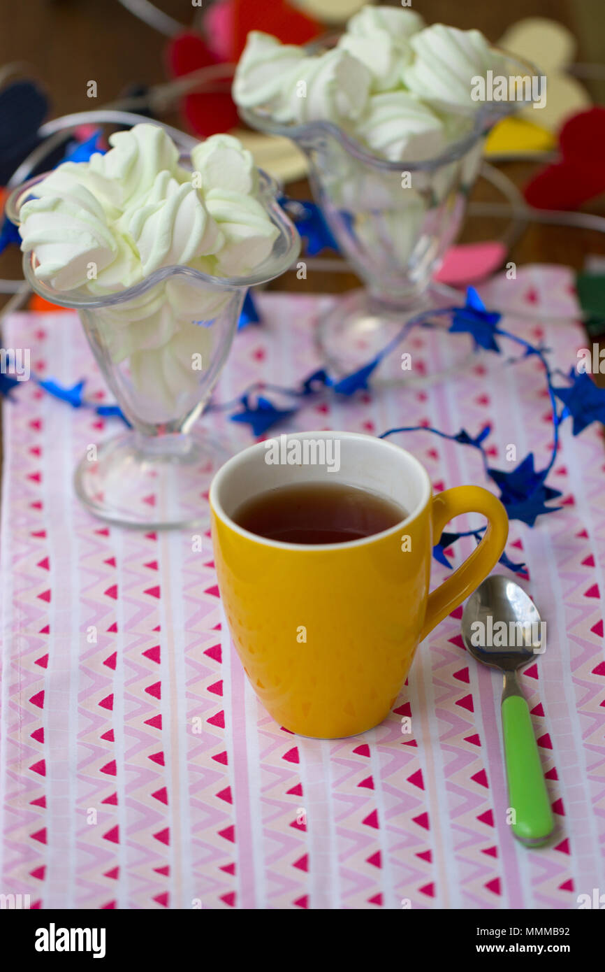 Tea in yellow cup with candy for breakfast Stock Photo - Alamy