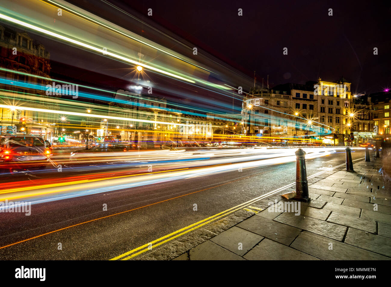Cars and buses cause streaks across the night sky in front of Trafalgar ...