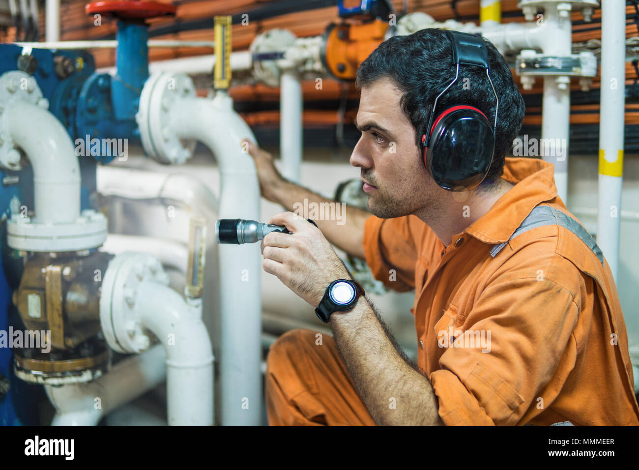 Marine engineer inspecting ship's engine with torchlight in engine ...