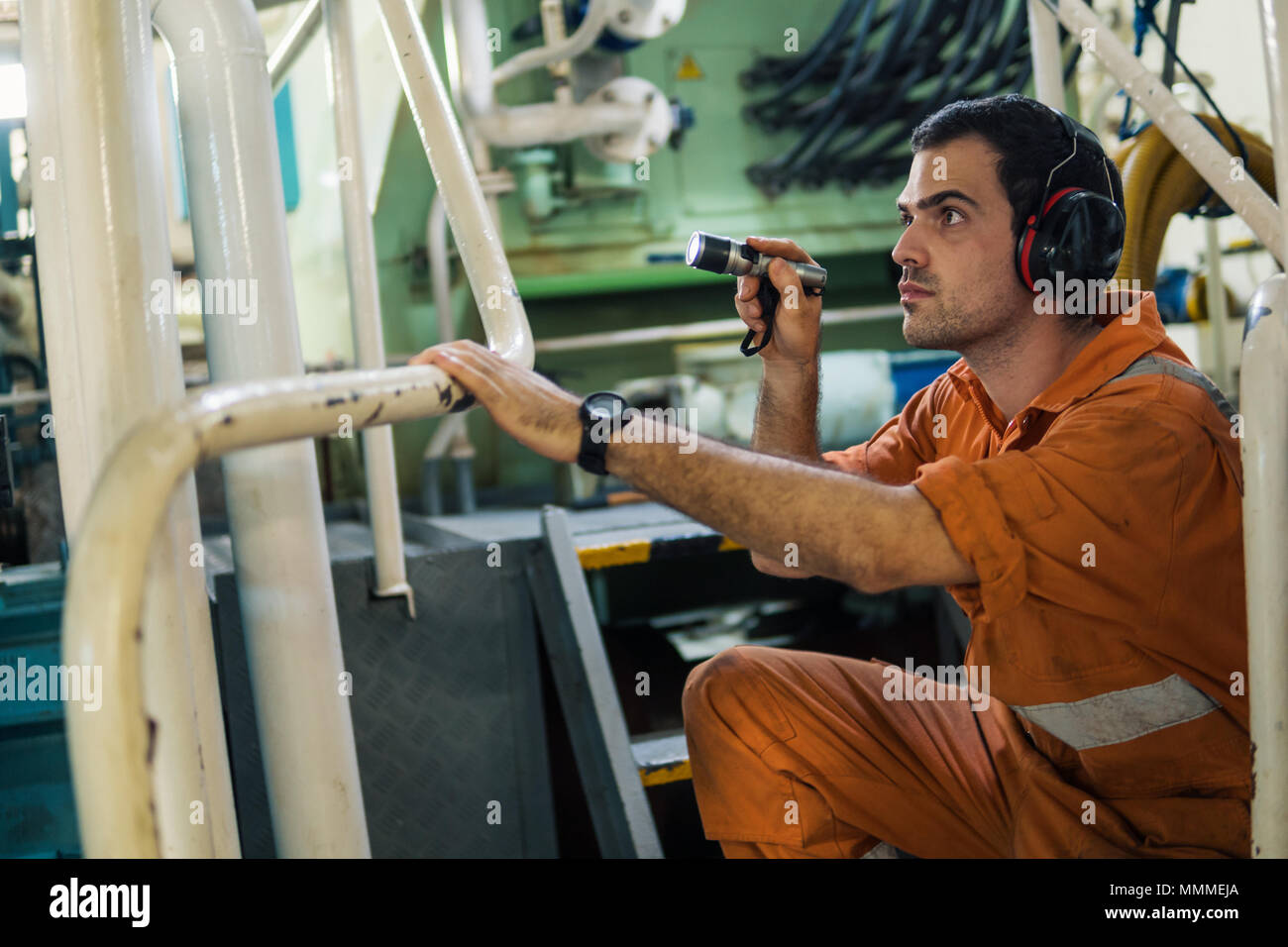 Marine engineer inspecting ship's engine with torchlight in engine ...