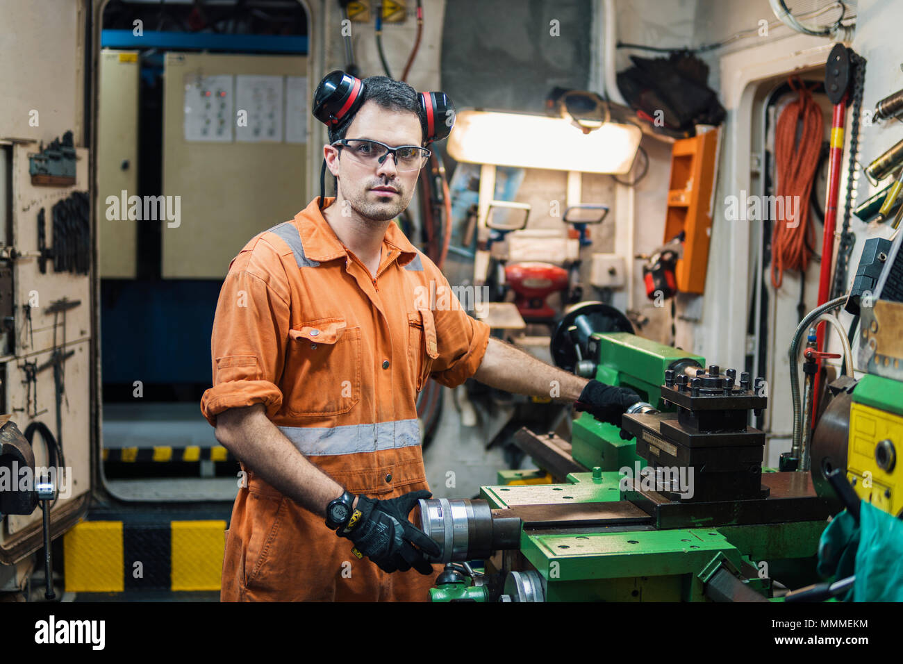 Marine engineer working in ship's workshop in engine control room ECR ...