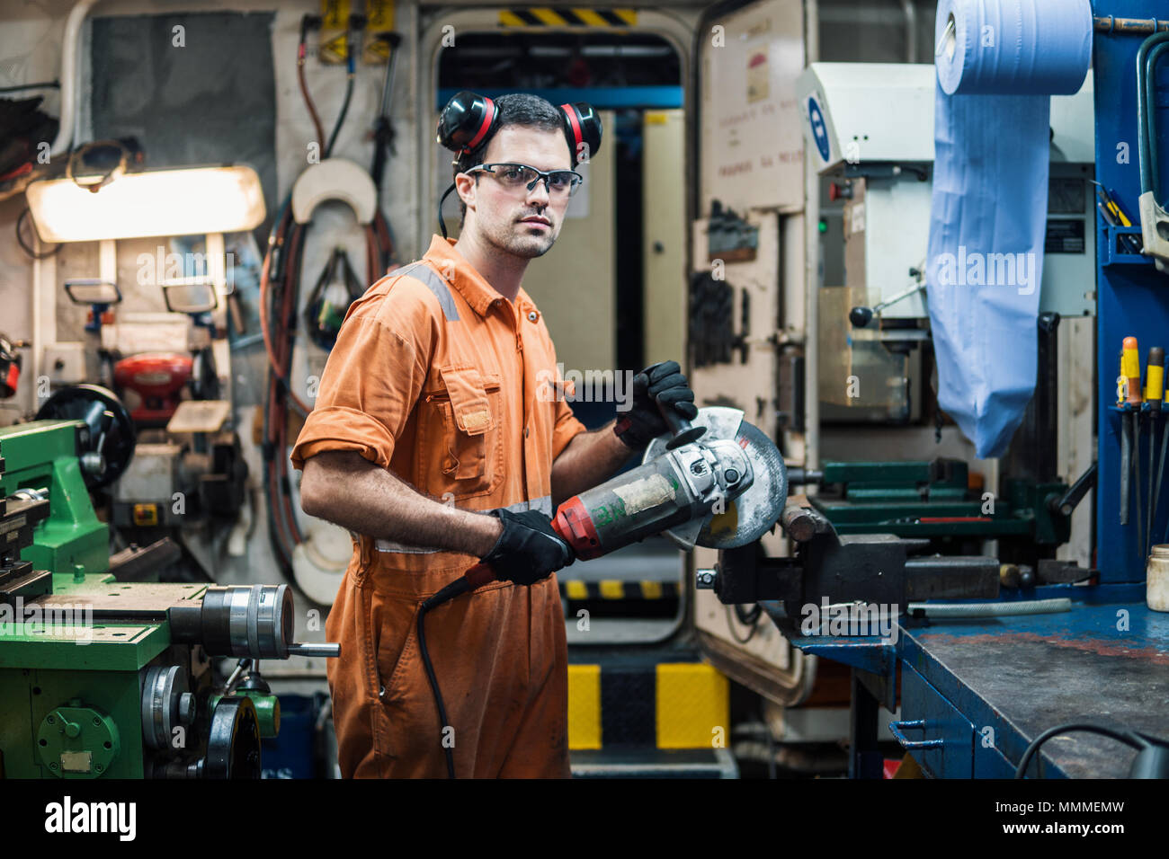Marine engineer working in ship's workshop in engine control room ECR ...