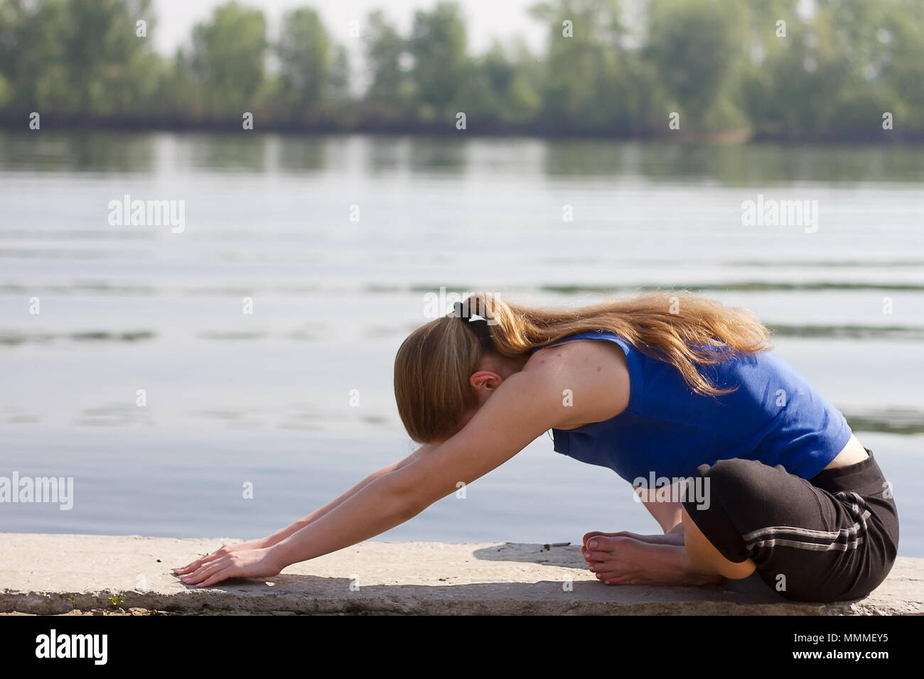 Yoga Woman on a dock by the river Stock Photo - Alamy