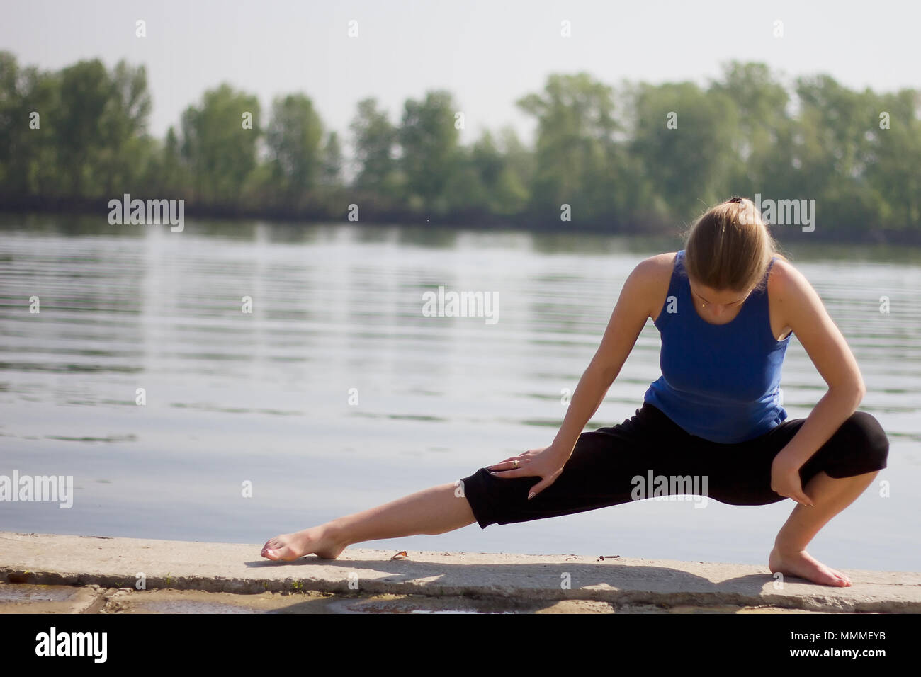 Yoga Woman on a dock by the river Stock Photo - Alamy