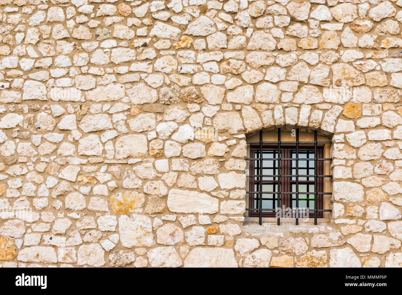 A small window of a dungeon with a lattice and a stone wall with space ...
