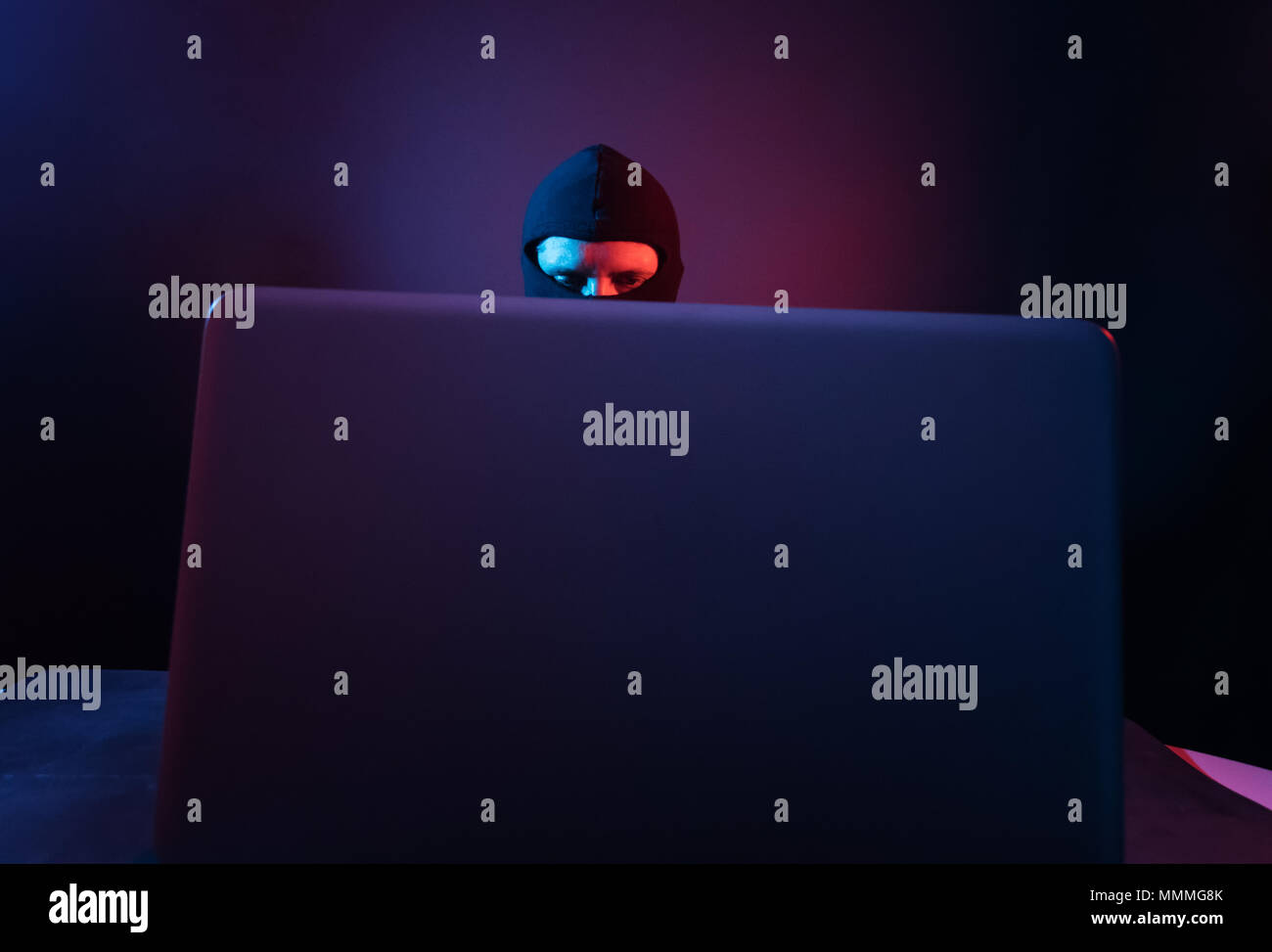 Angry computer hacker in suit stealing data from laptop illuminated by ...
