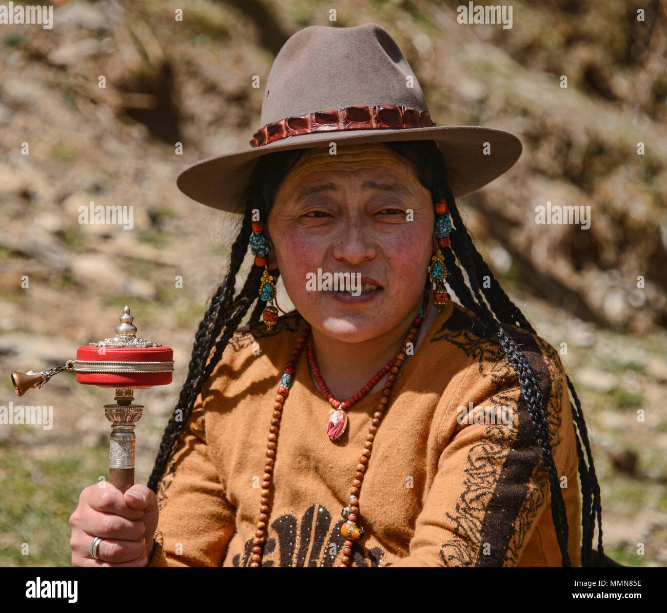 Tibetan pilgrim spins a prayer wheel outside the holy Bakong Scripture ...