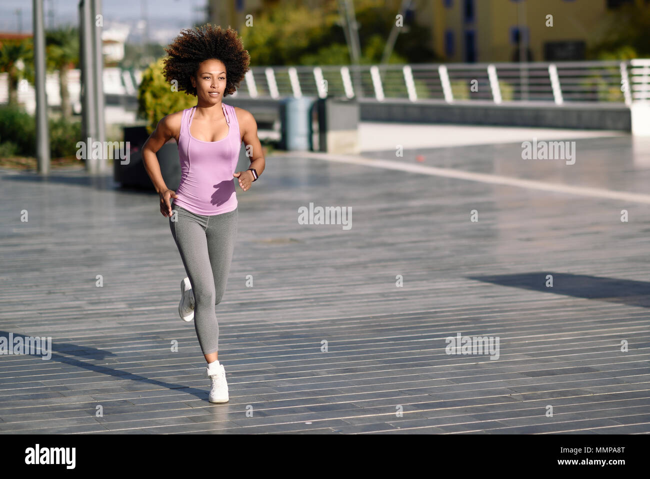 Black woman, afro hairstyle, running outdoors in urban road. Young ...