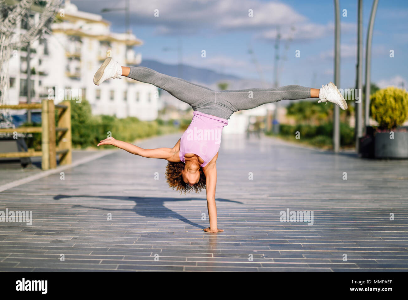 Black fit woman doing fitness acrobatics in urban background. Young ...
