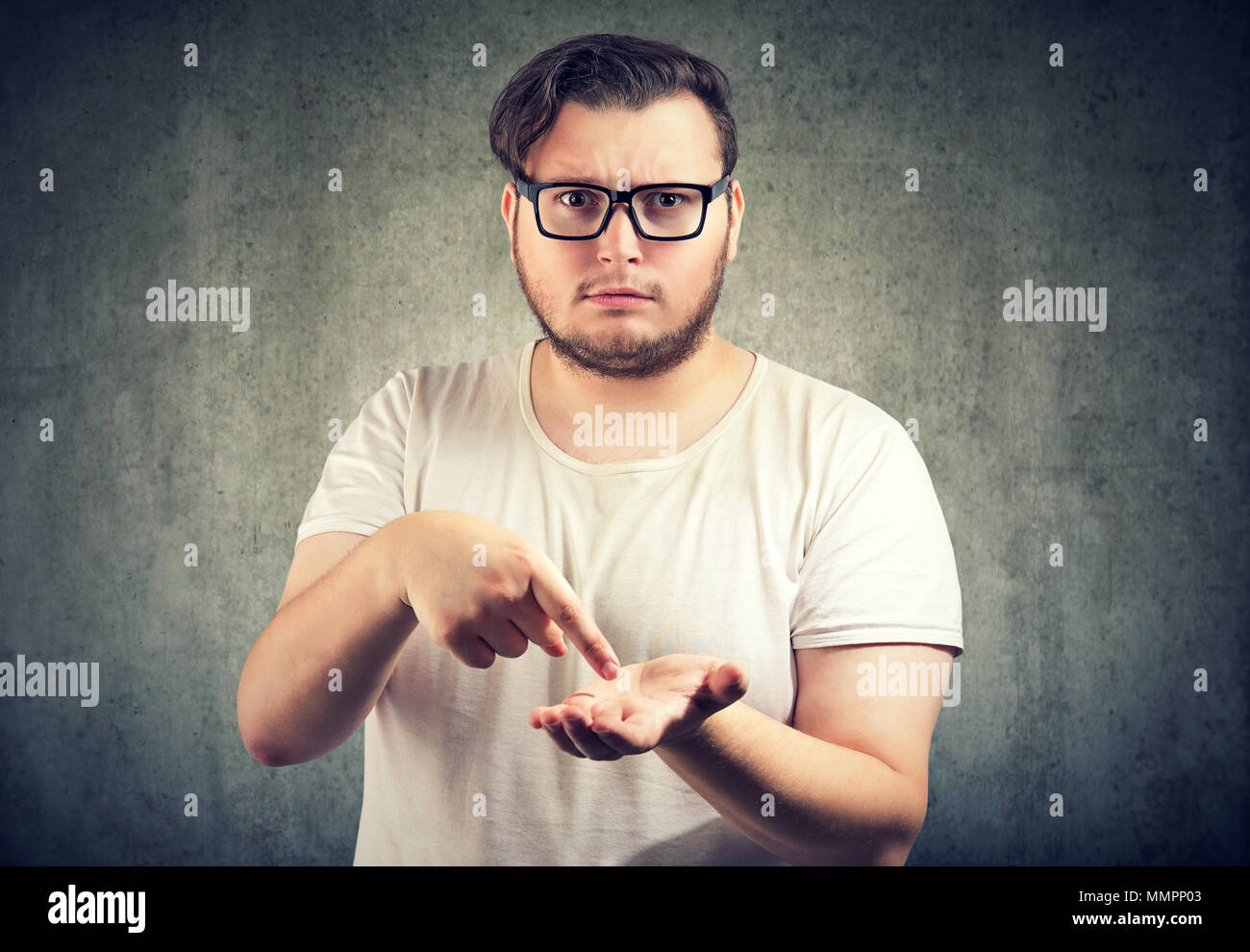 Young serious chubby man asking for more money to pay back debt Stock ...