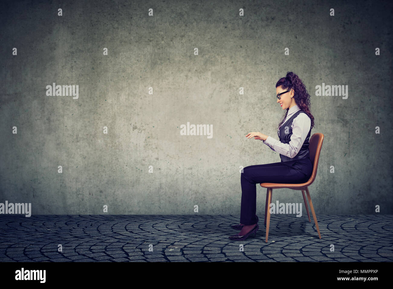 Side view of an employee woman sitting at invisible table pretending to ...