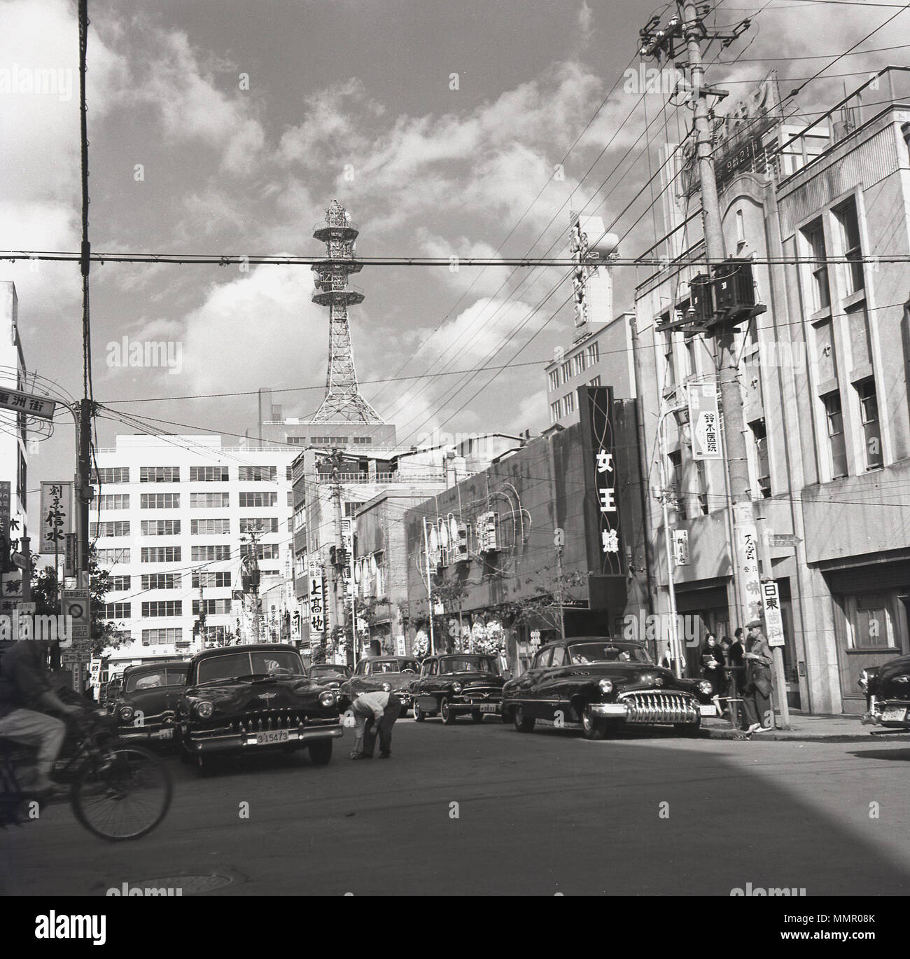 1950s, street in Tokyo, Japan with parked cars. Post-WW2 saw many large ...