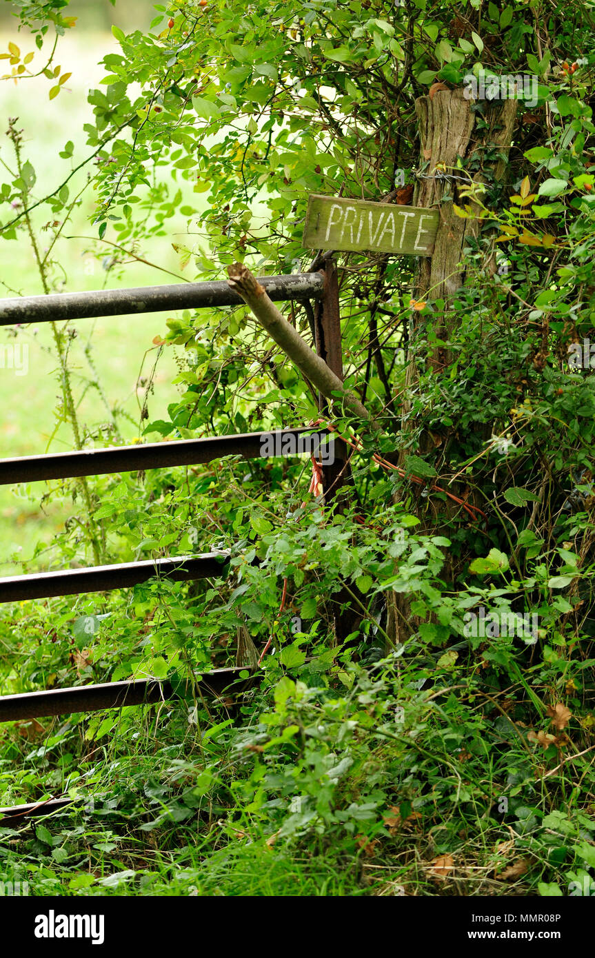 an old farmyard gate in the countryside with a handwritten private sign ...