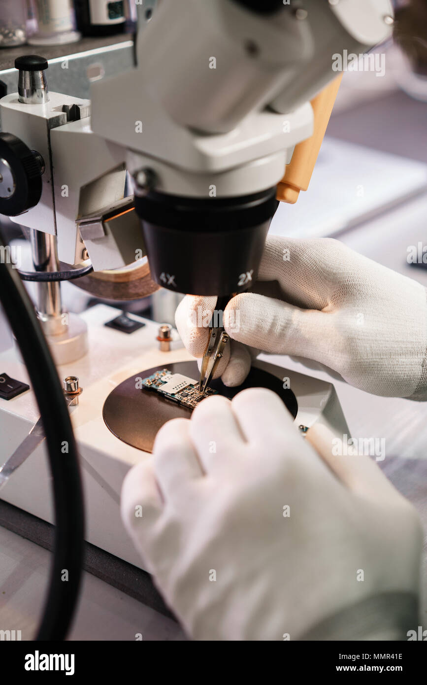 Work with a microscope. Microelectronics device. Close-up hands of a ...