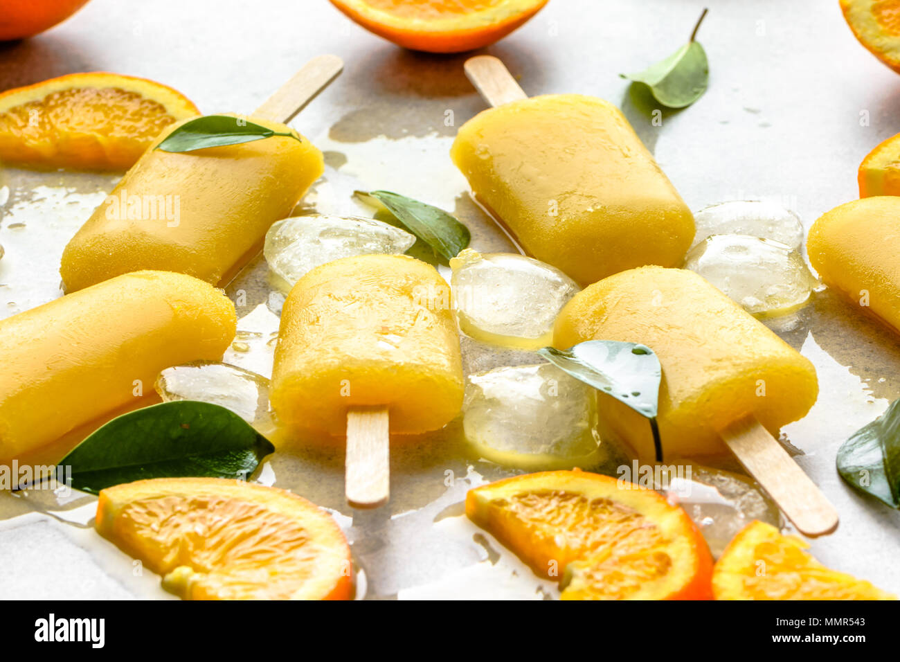 Orange popsicles with frozen juice and ice cubes, summer refreshing ...