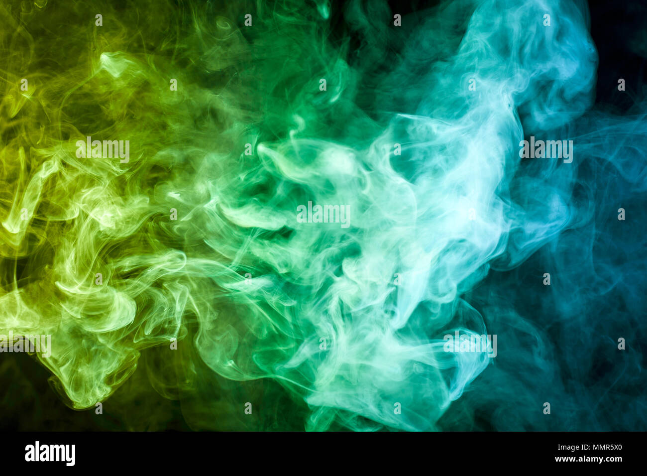 Colorful yellow, blue and green smoke on a black isolated background ...