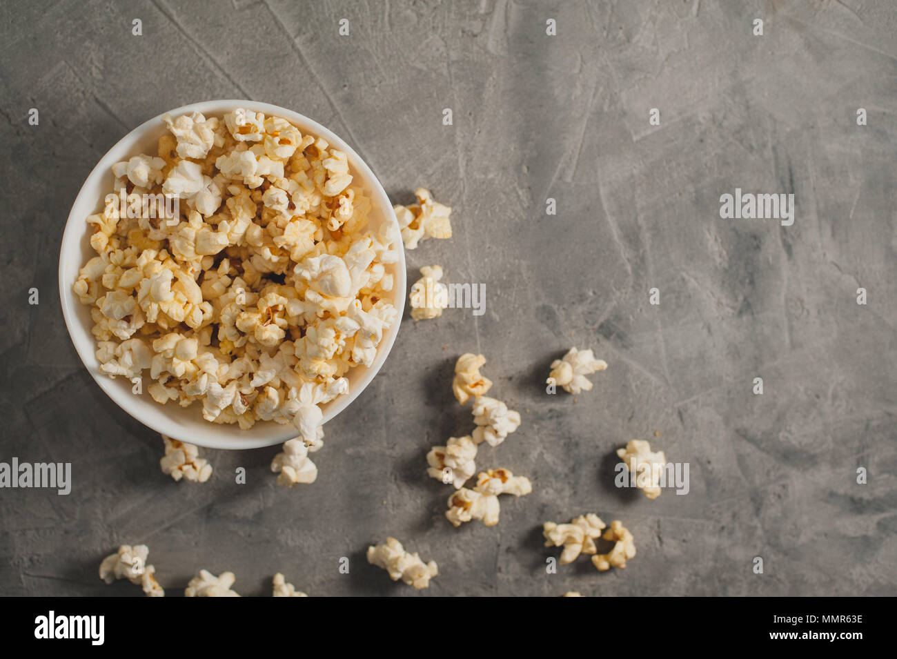 popcorn in a white plate on a concrete gray background Stock Photo - Alamy