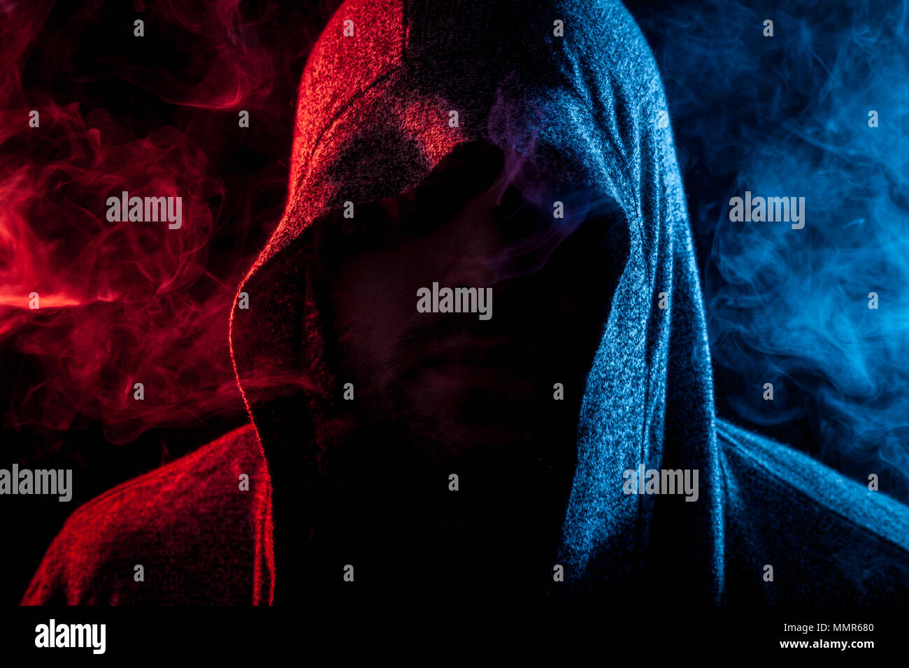 A young man in a black cape smokes and exhales large clouds of colored ...