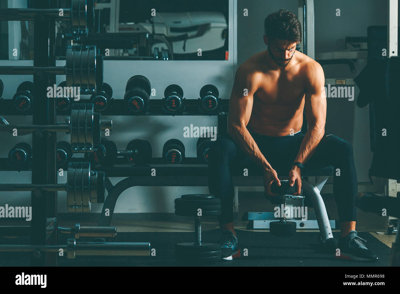 Portrait of strong and handsome young man doing exercise with dumbbells ...