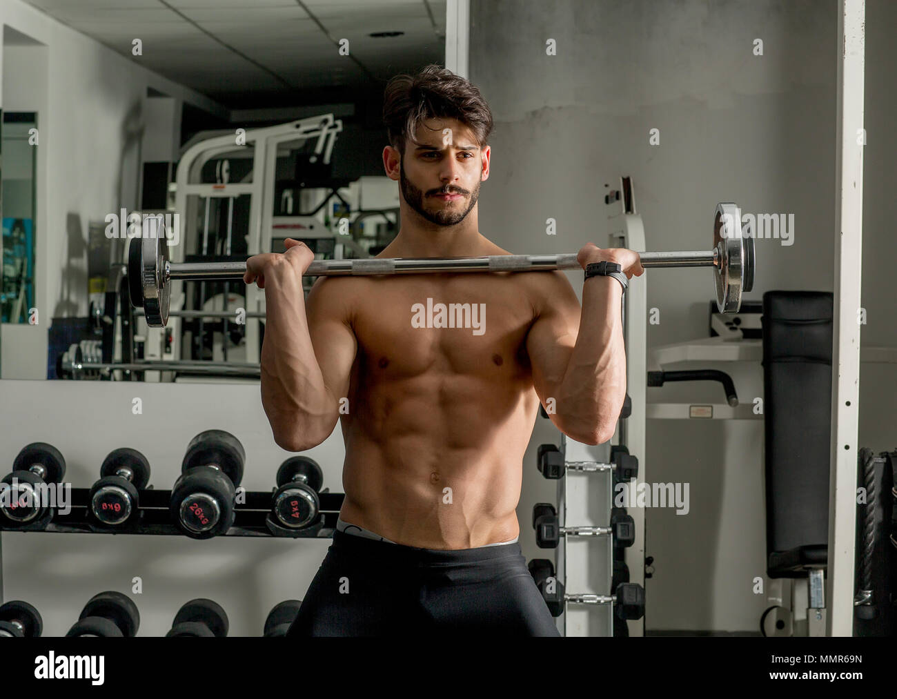 Portrait of strong and handsome young man doing exercise with dumbbells ...