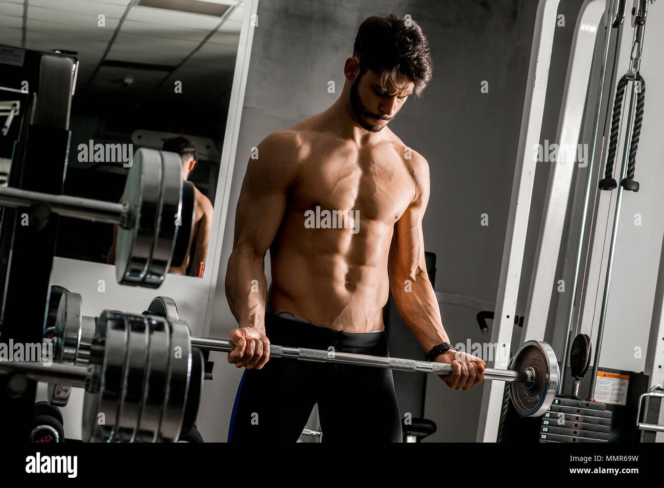 Portrait of strong and handsome young man doing exercise with dumbbells ...