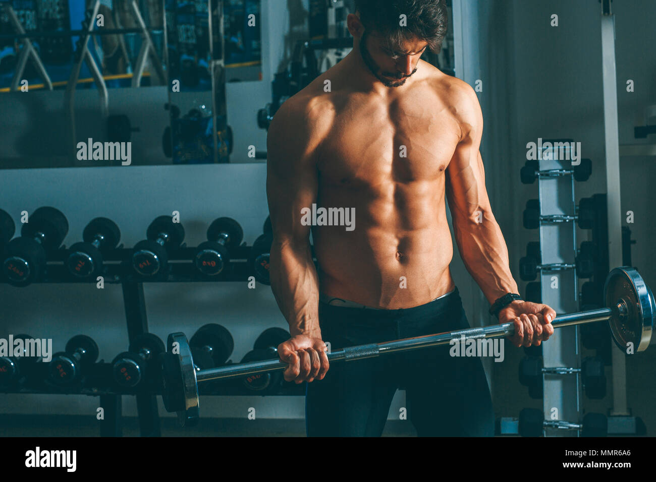 Portrait of strong and handsome young man doing exercise with dumbbells ...
