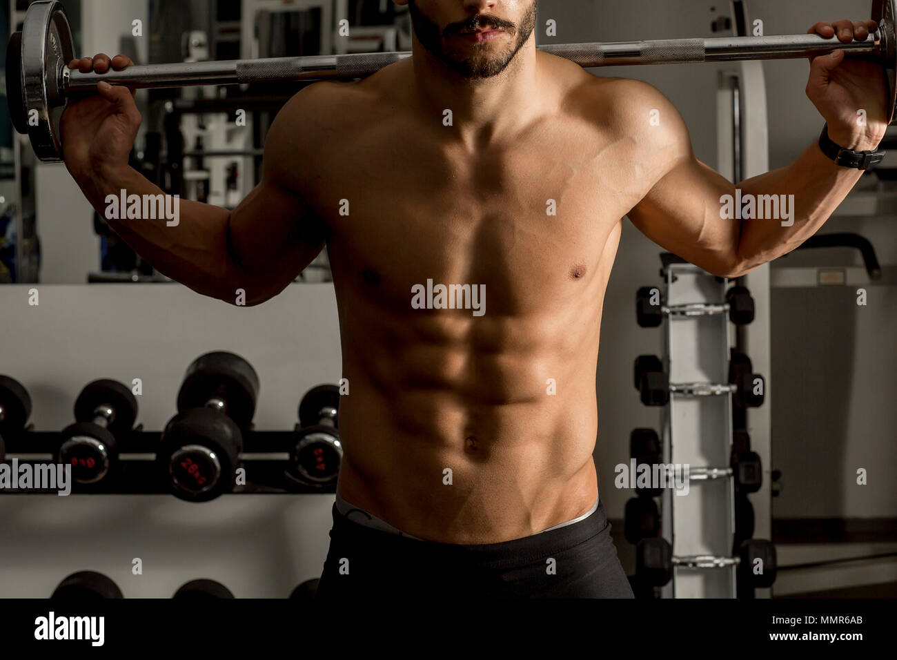 Portrait of strong and handsome young man doing exercise with dumbbells ...