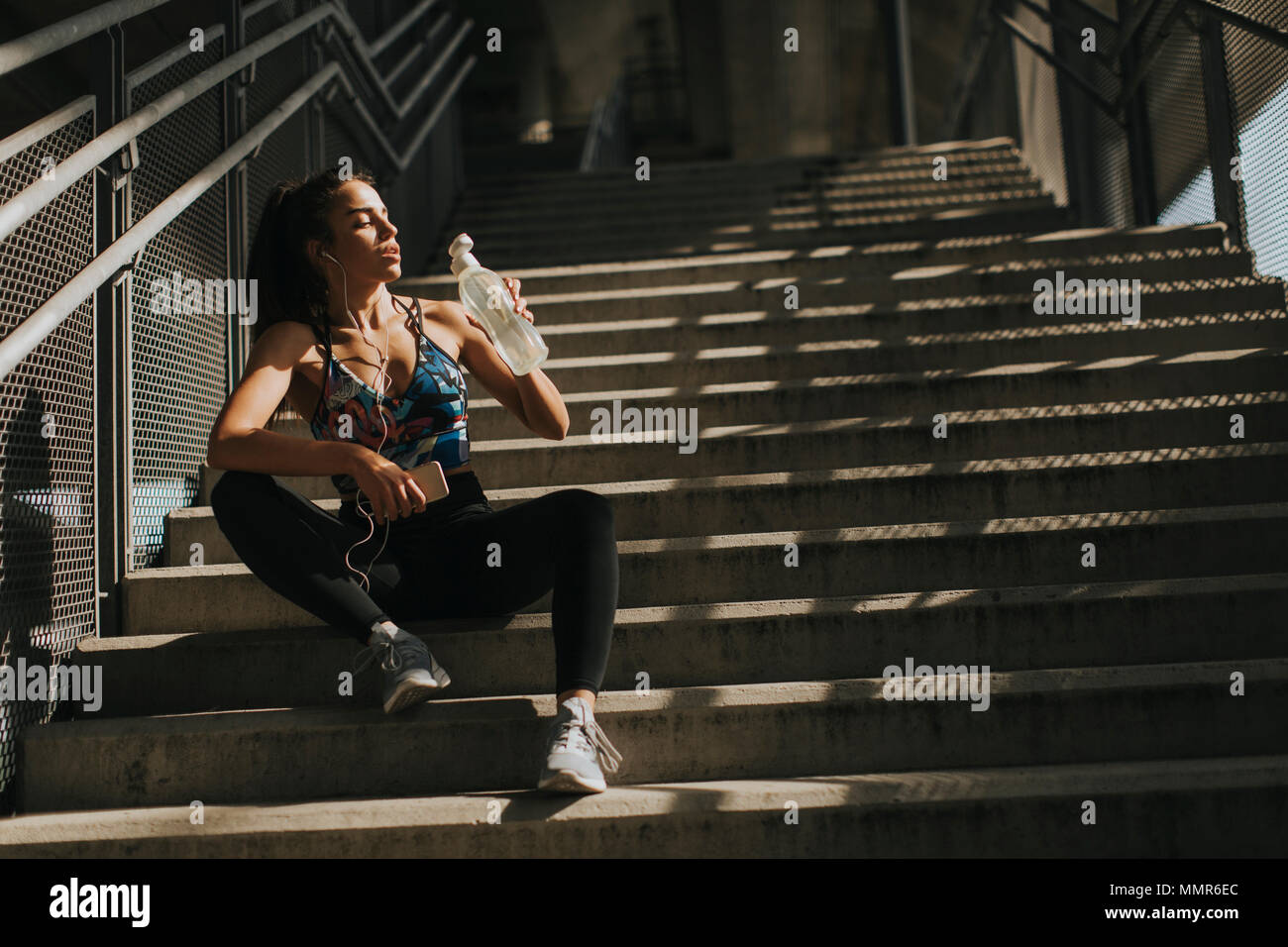 Portrait of pretty young female runner resting on stairs Stock Photo ...