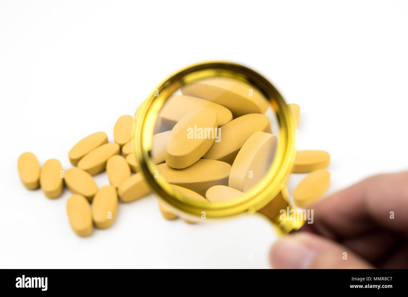 Orange medicine tablet is being examinate by magnifier Stock Photo - Alamy