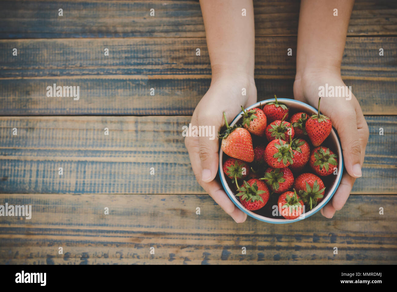 Hand of people holding strawberry in bowl on wood table, concept as ...