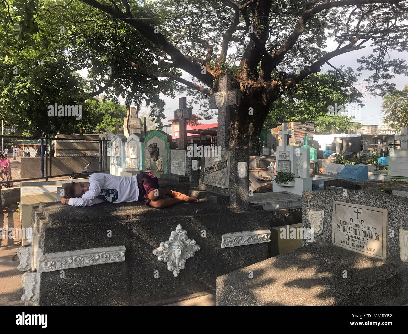 20 April 2018, Philippines, Manila: A boy sleeps on a grave in the ...
