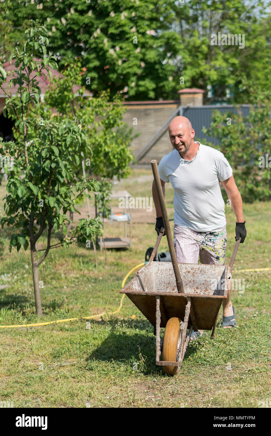 man pushing wheelbarrow. Young man pushing a wheelbarrow on the farm ...