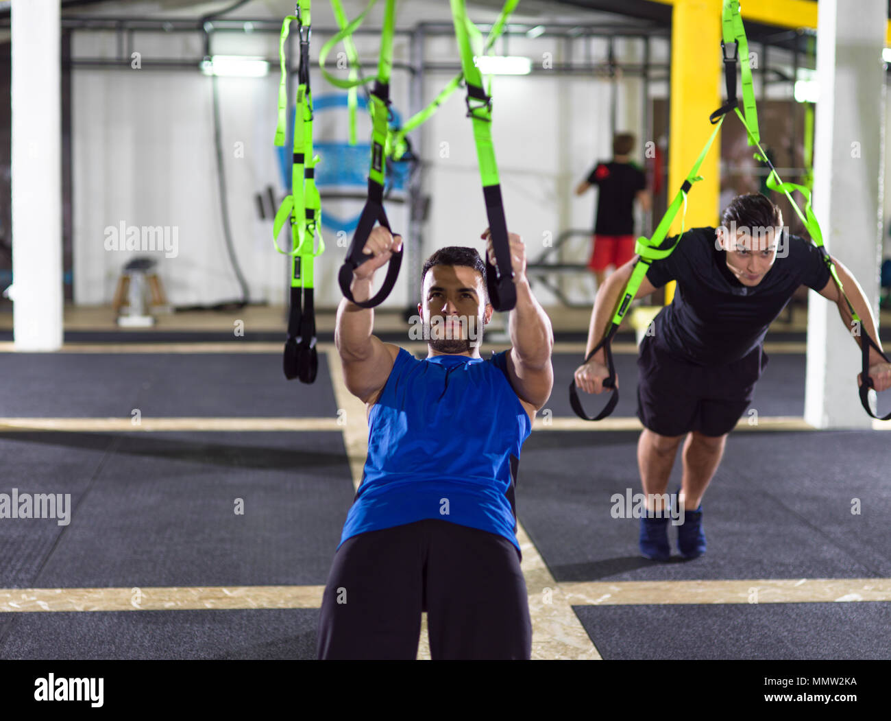 two young athlete men working out pull ups with gymnastic rings at the ...