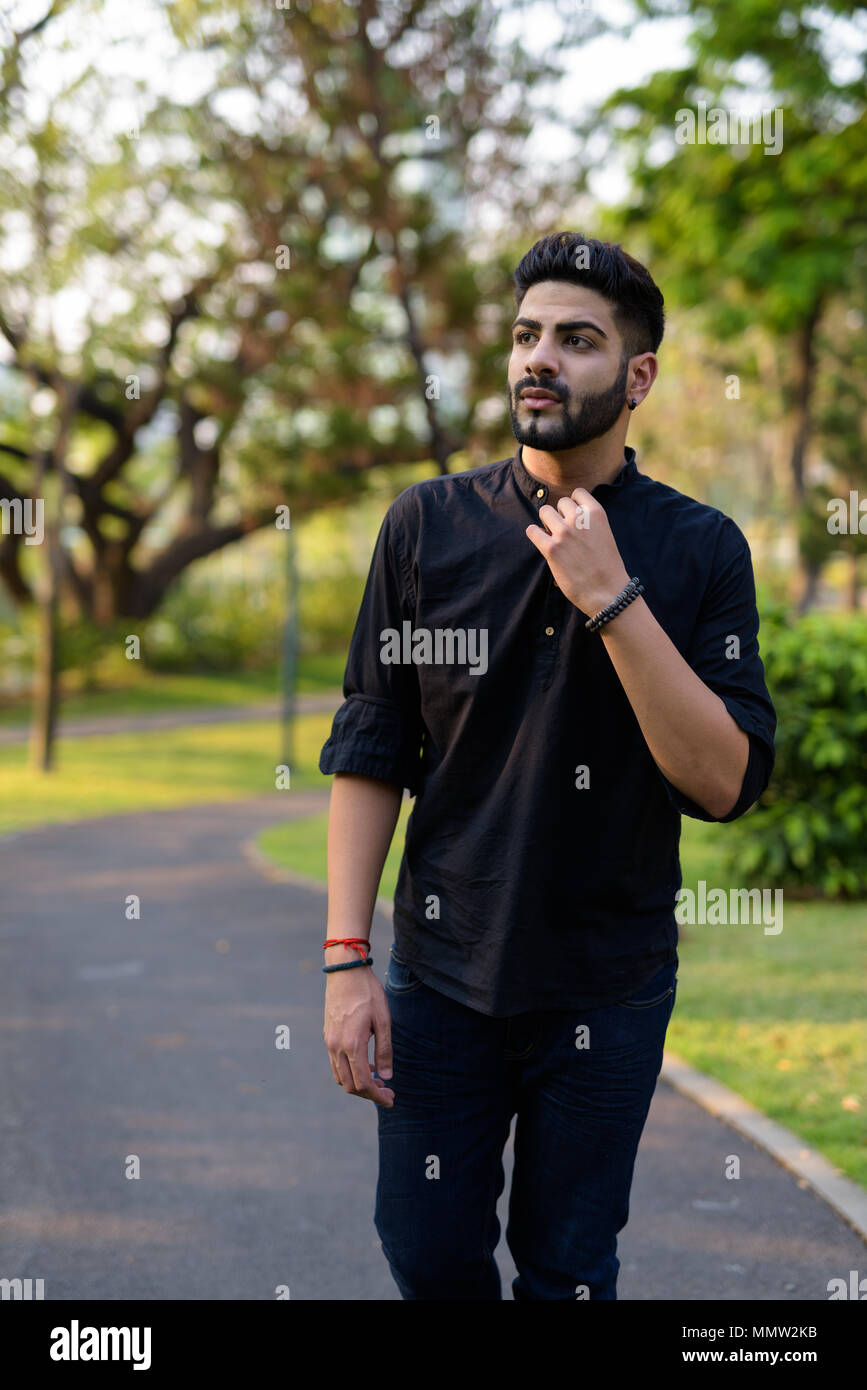Young handsome Indian man thinking while walking on the road at Stock ...