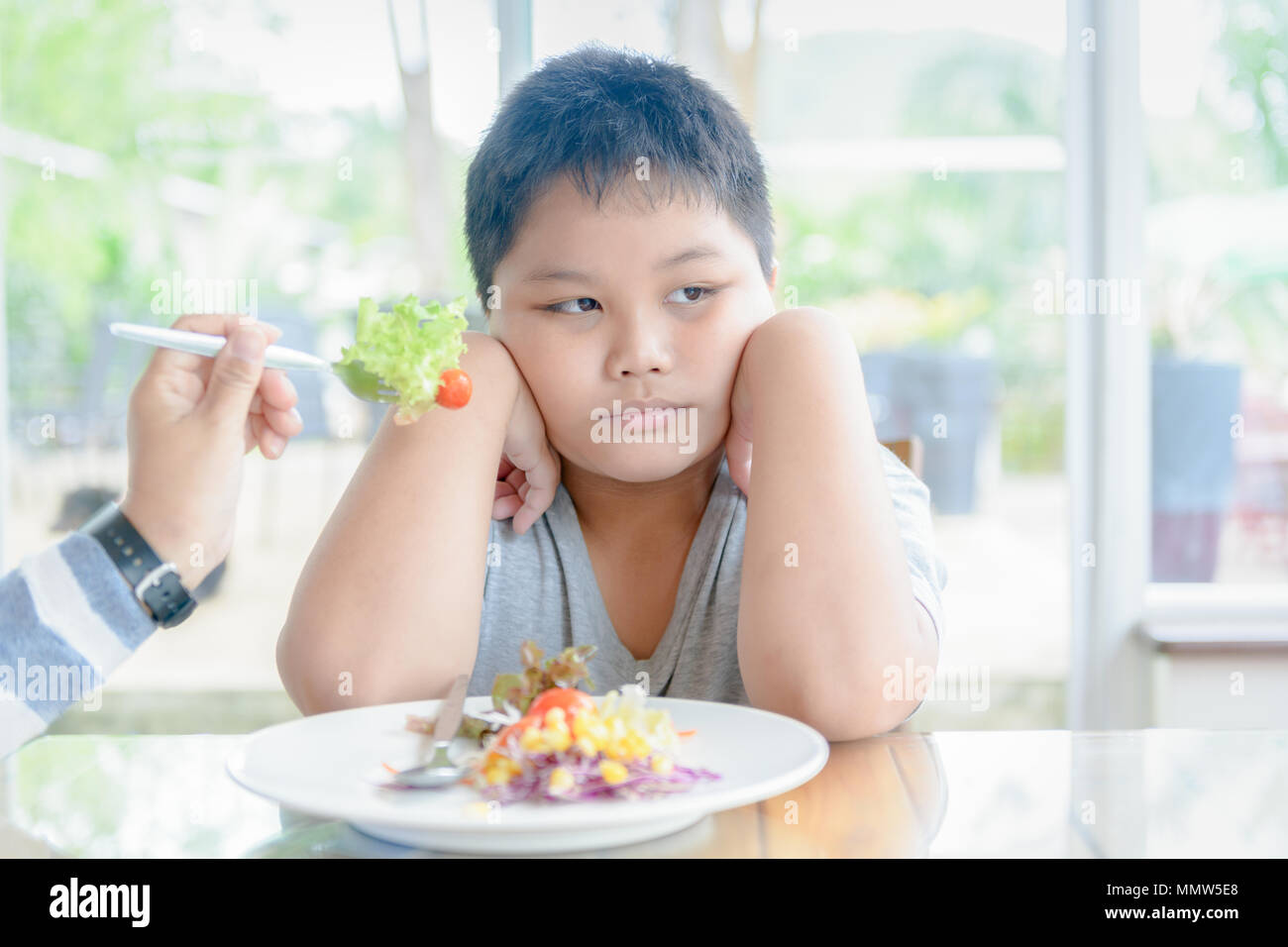 Anorexia, obese fat boy with expression of disgust against vegetables ...