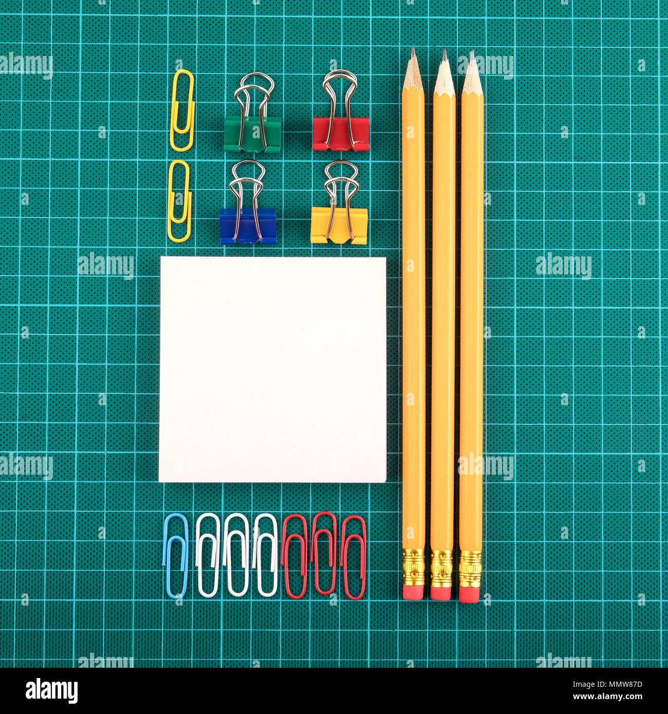 Paper clips, pencils and note sheet on checked green backgound Stock ...