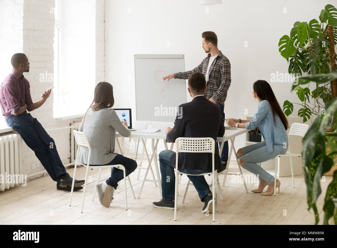 Casual businessman giving presentation to colleagues in the office ...