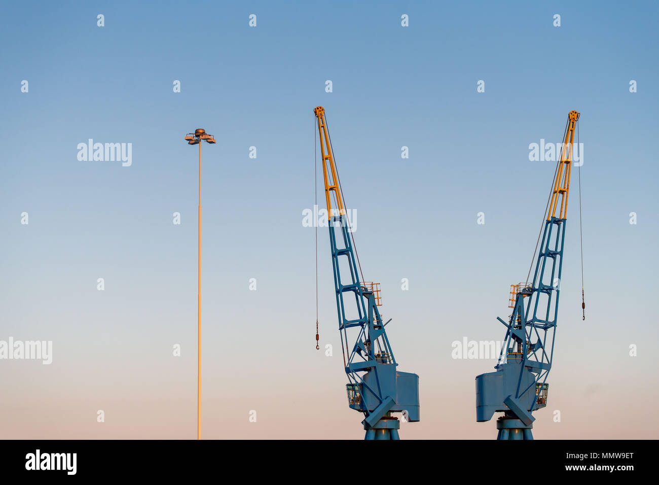 Two blue industrial cranes seen at a port in Cardiff, Wales, Uk, during ...