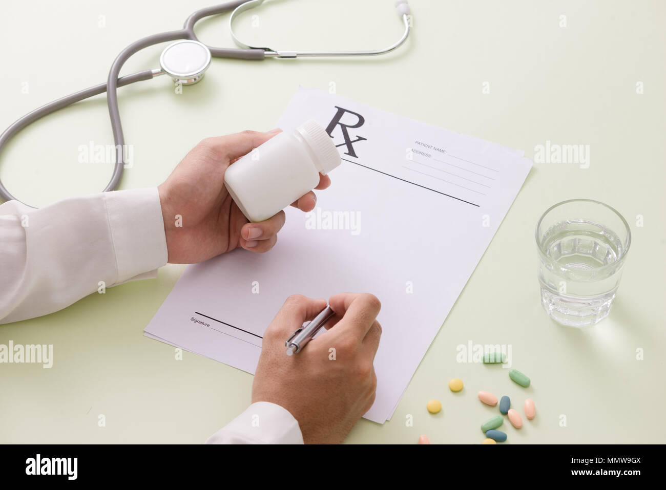 Top view of a doctor's hand writing a prescription. A pill bottle and ...